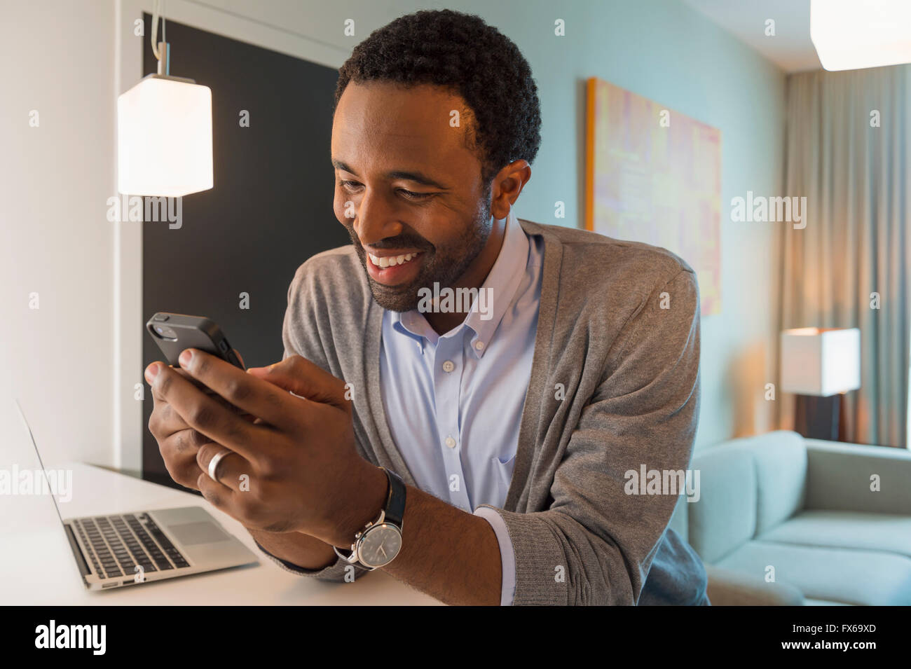 Black man using cell phone in living room Stock Photo - Alamy