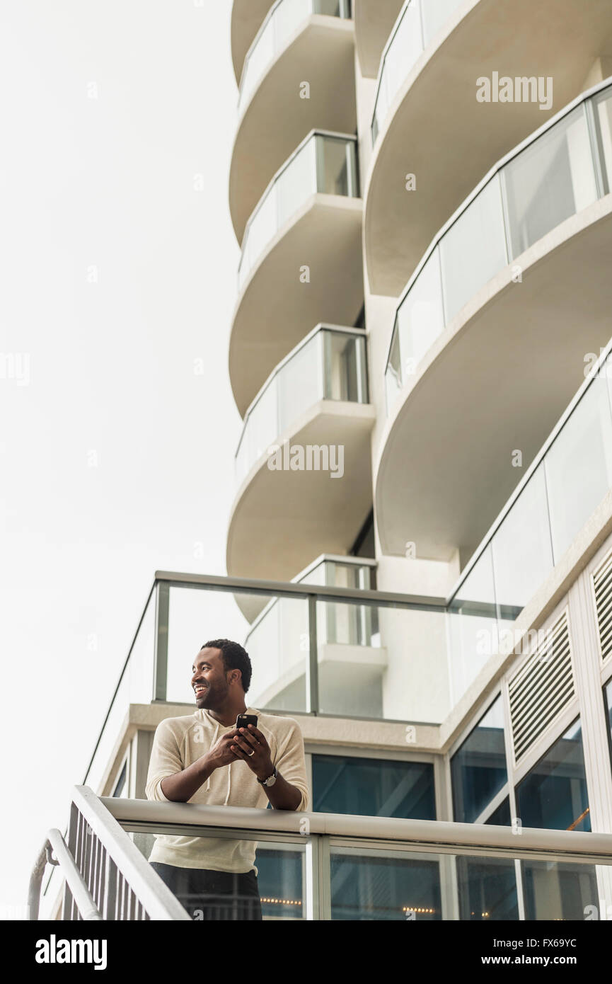 Black man using cell phone on balcony Stock Photo - Alamy