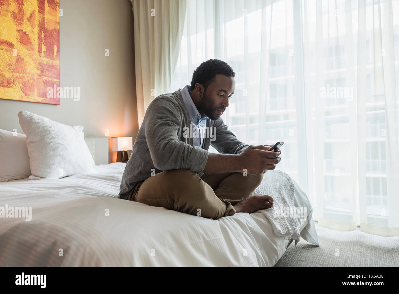 Black man using cell phone on bed Stock Photo - Alamy