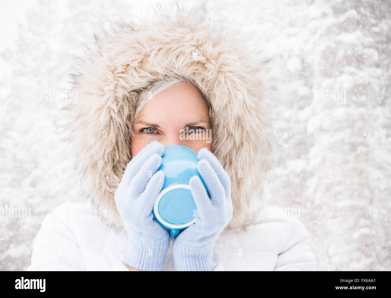 Caucasian woman drinking coffee in snow Stock Photo - Alamy