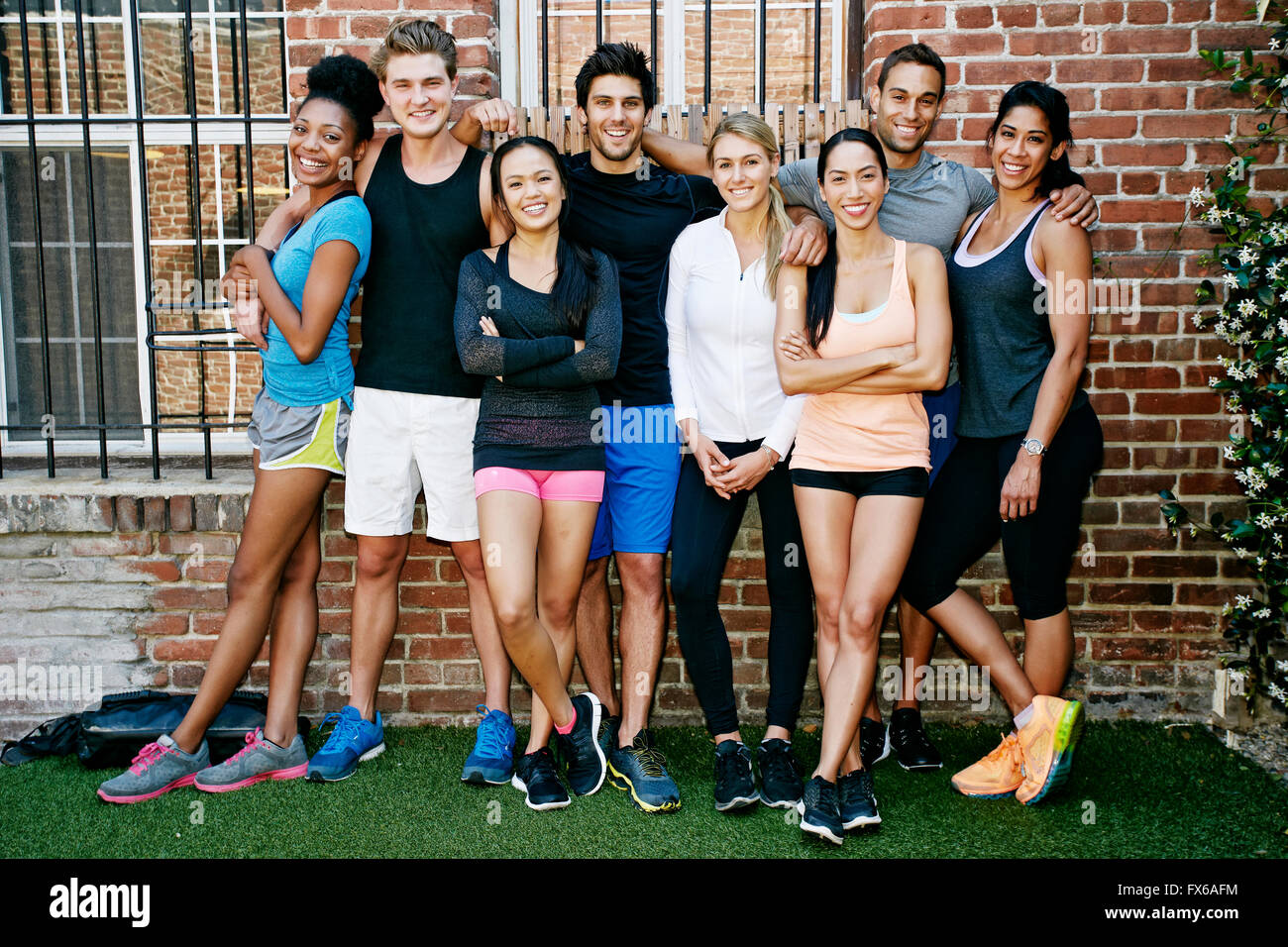 Friends smiling near brick wall Stock Photo - Alamy