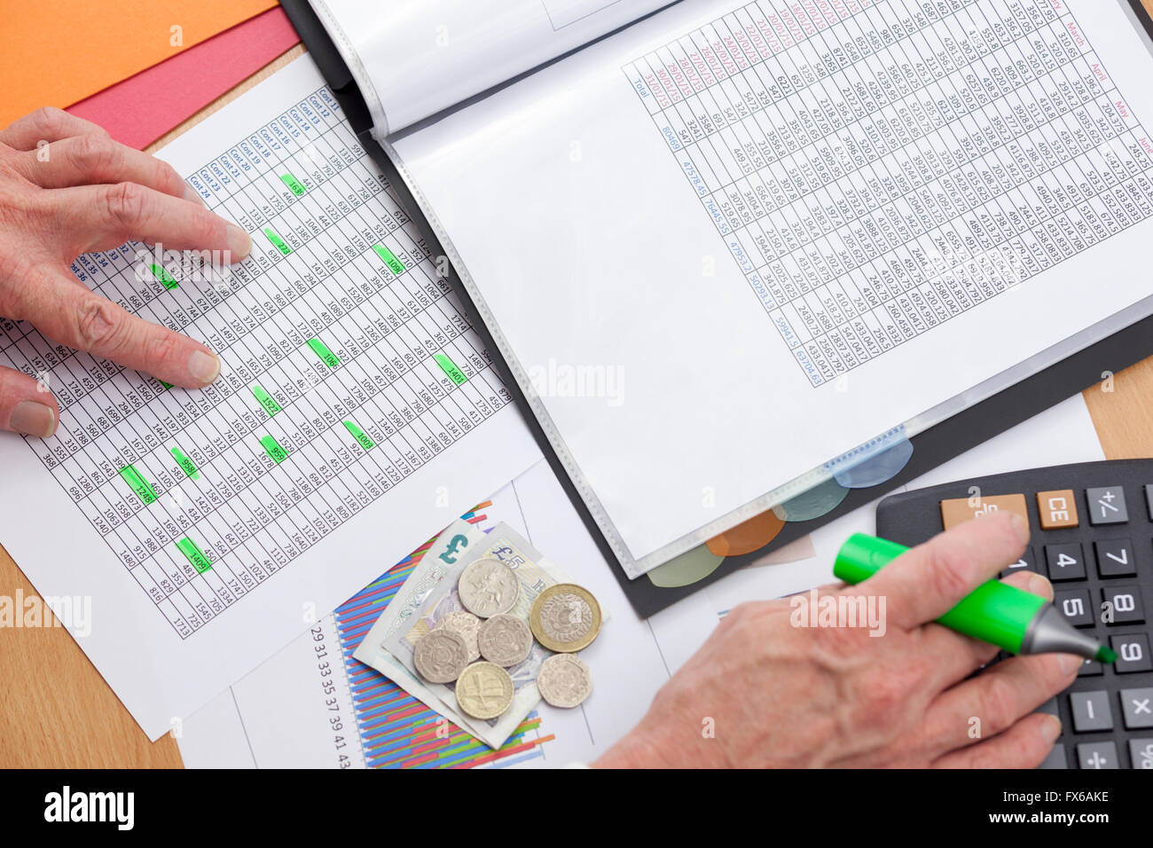 Busy financier at his desk using a calculator to check a sales report ...