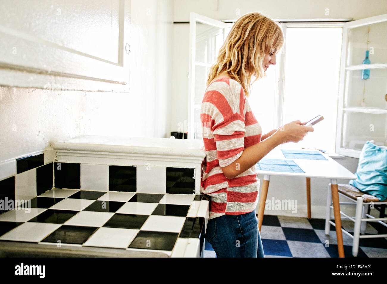Young woman texting in kitchen hi-res stock photography and images - Alamy