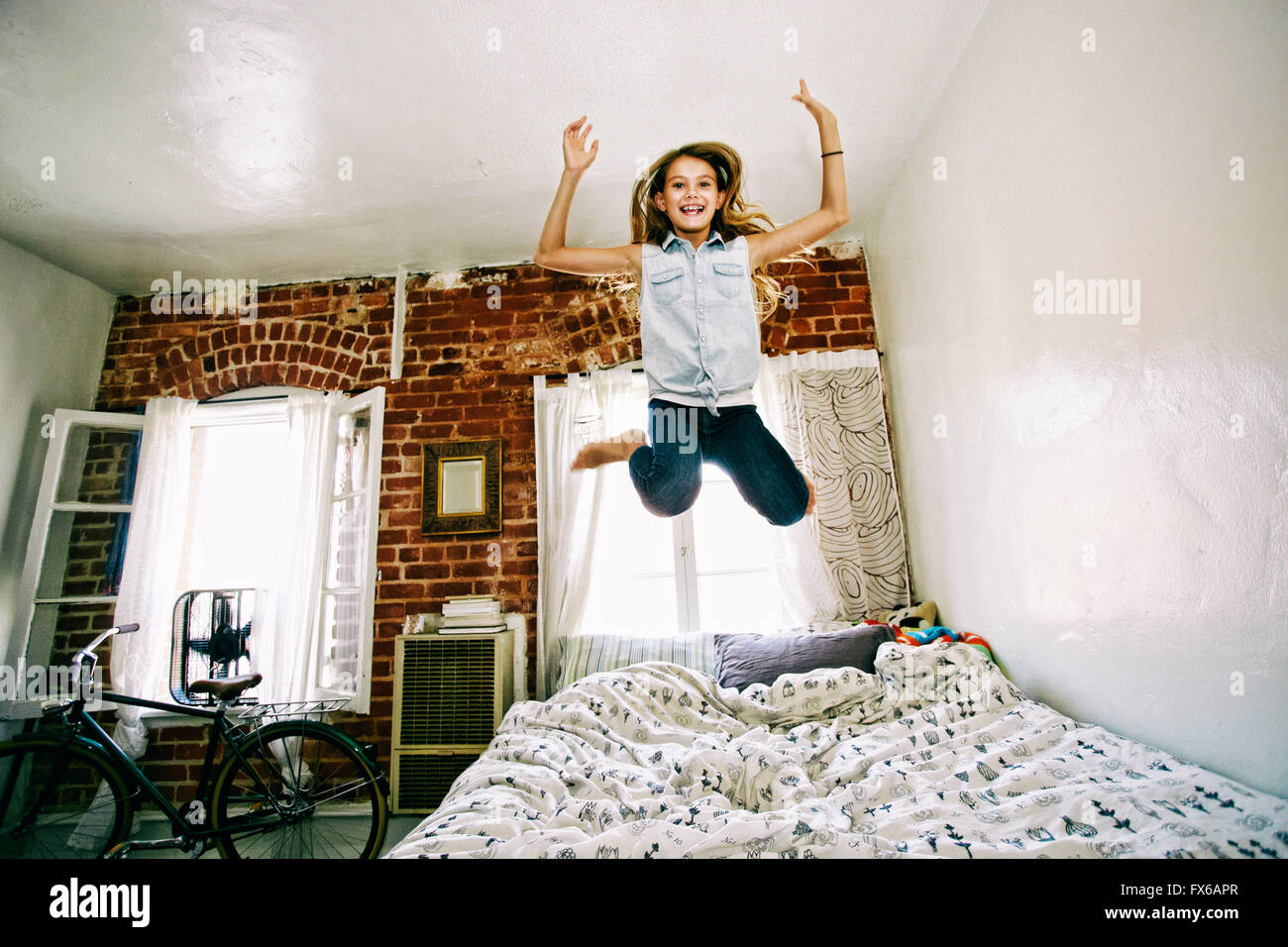 Native American girl jumping on bed Stock Photo - Alamy