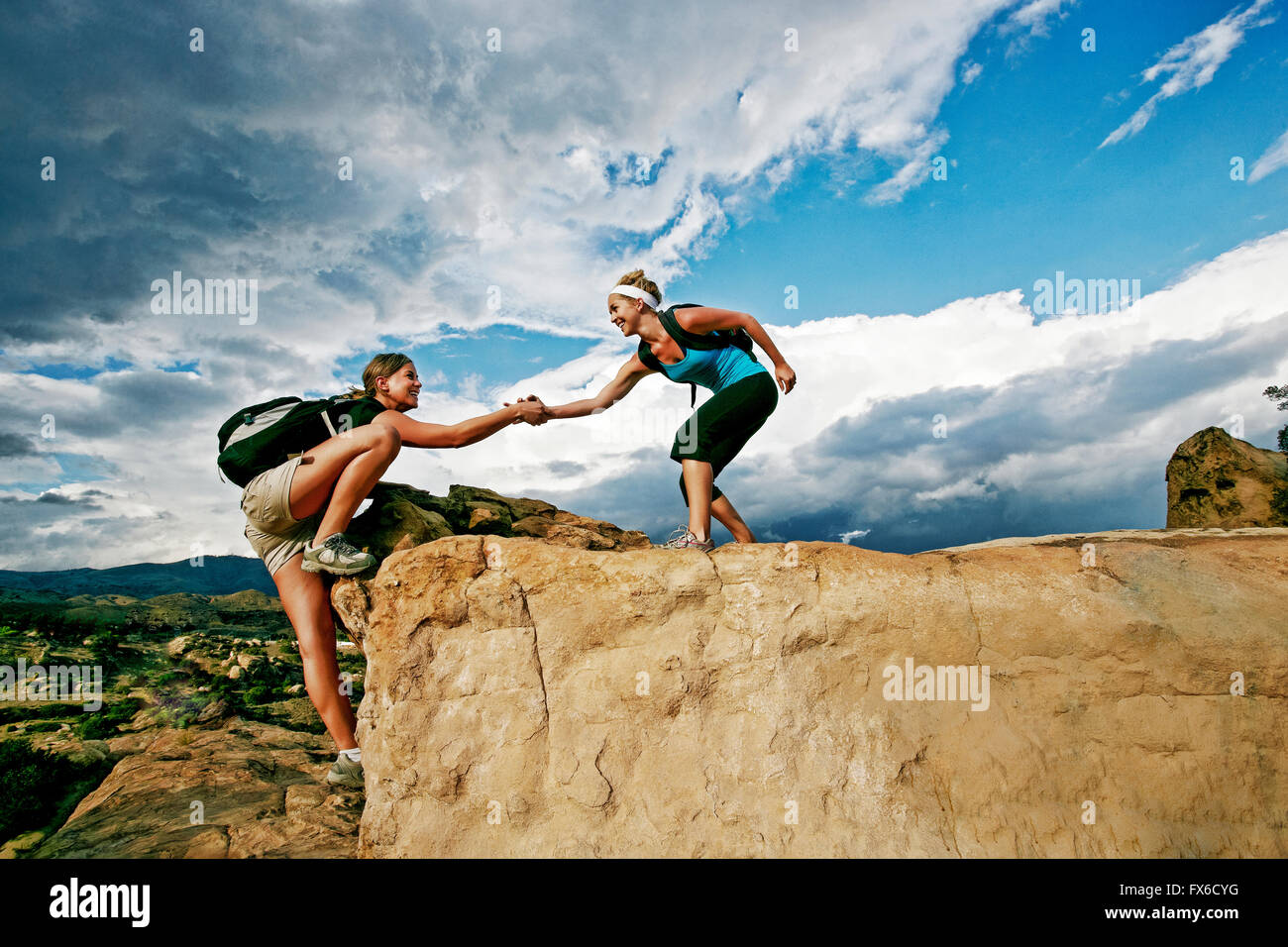 Woman helping friend climb rock formation Stock Photo - Alamy