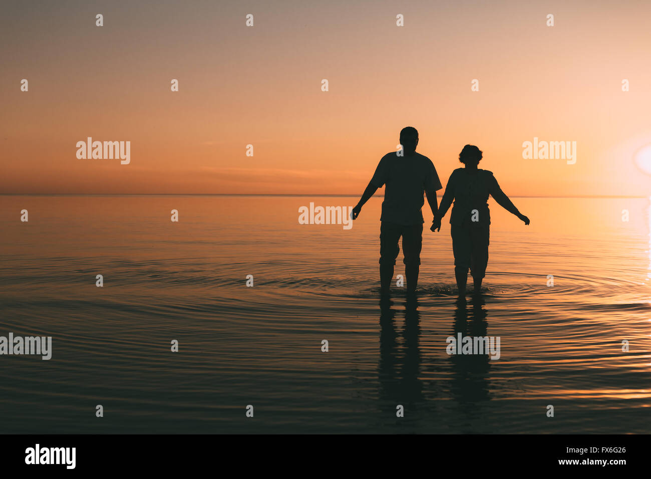 Silhouette of adult couple standing in the sea against a sunset Stock ...