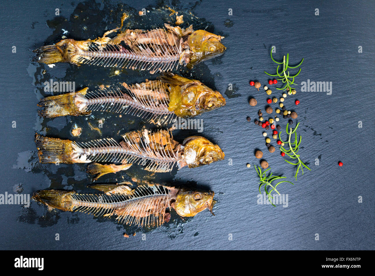 top view of fish skeleton bones and flavor peppers on slate background ...