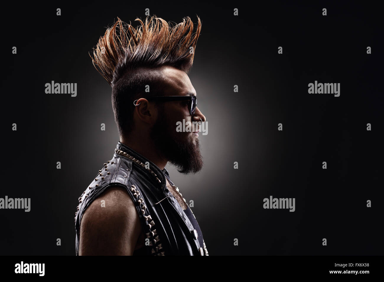 Profile shot of a young punk rocker with a Mohawk hairstyle on dark ...