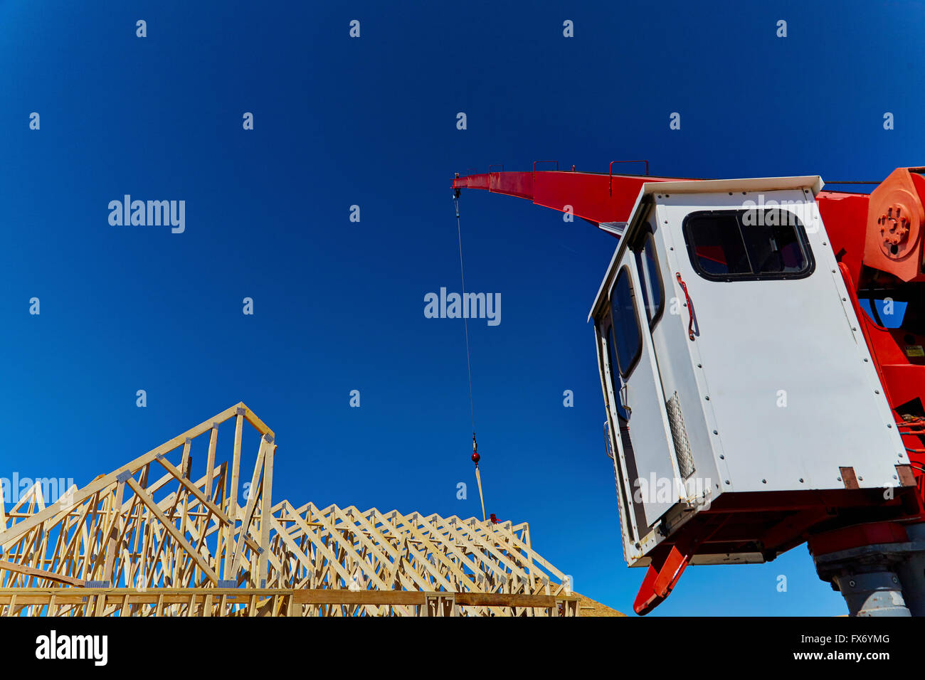 Crane lifting wood truss to roof of new home construction site Stock ...