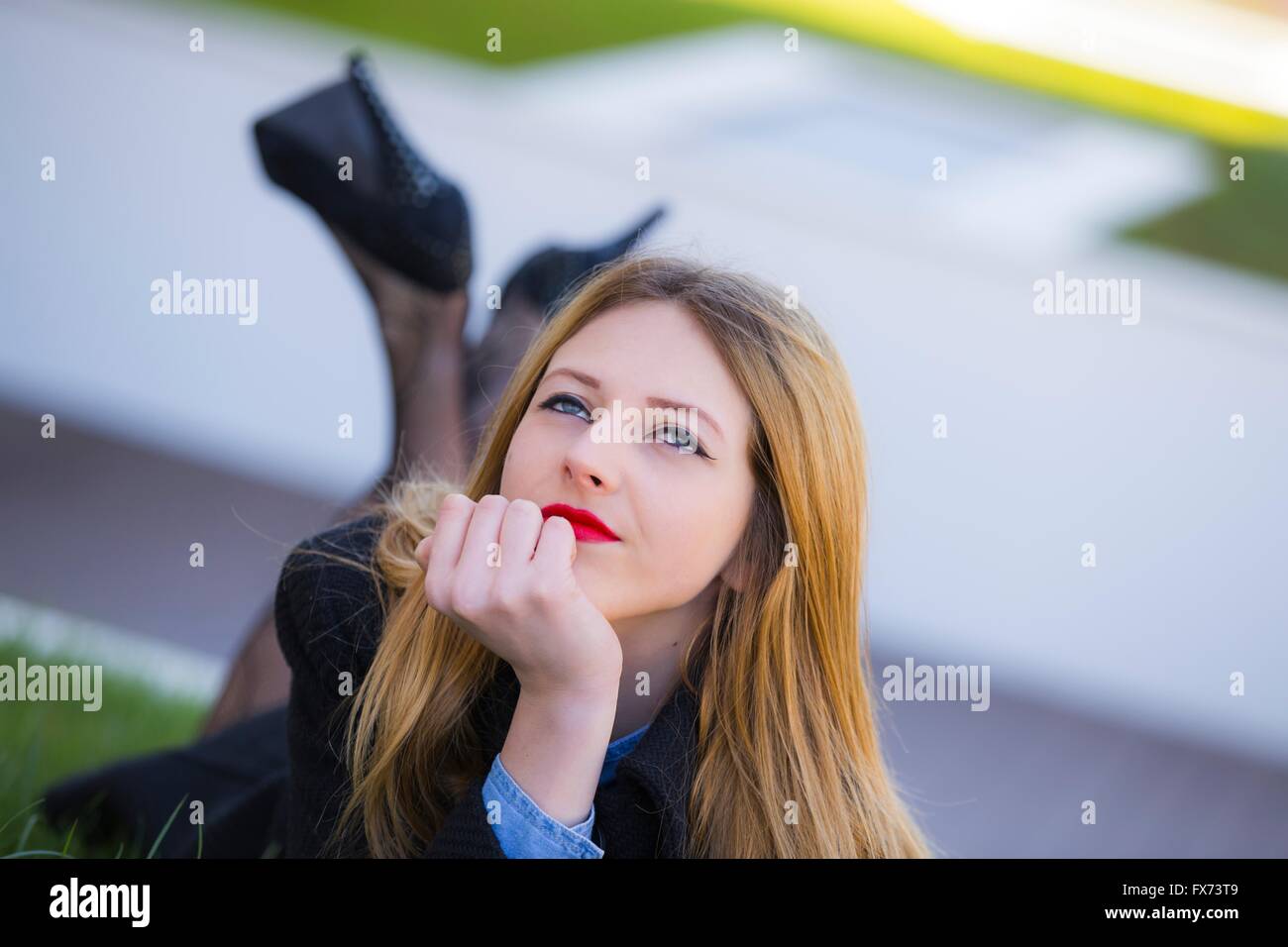 Daydreaming blonde fairhaired adolescent teen laying down on her tummy belly stomach crossed ...