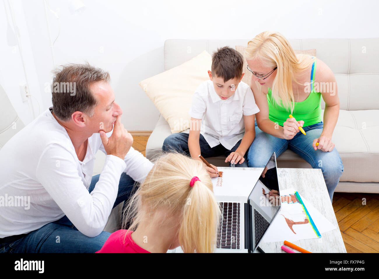 Kids drawing with happy parents on the couch Stock Photo - Alamy