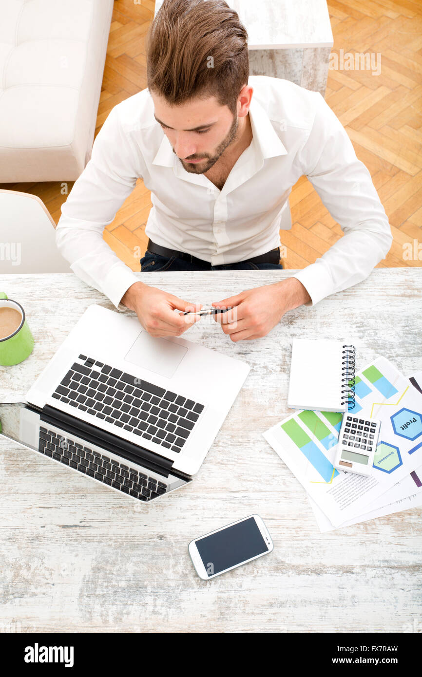 A young man sitting at the table with a laptop computer Stock Photo - Alamy