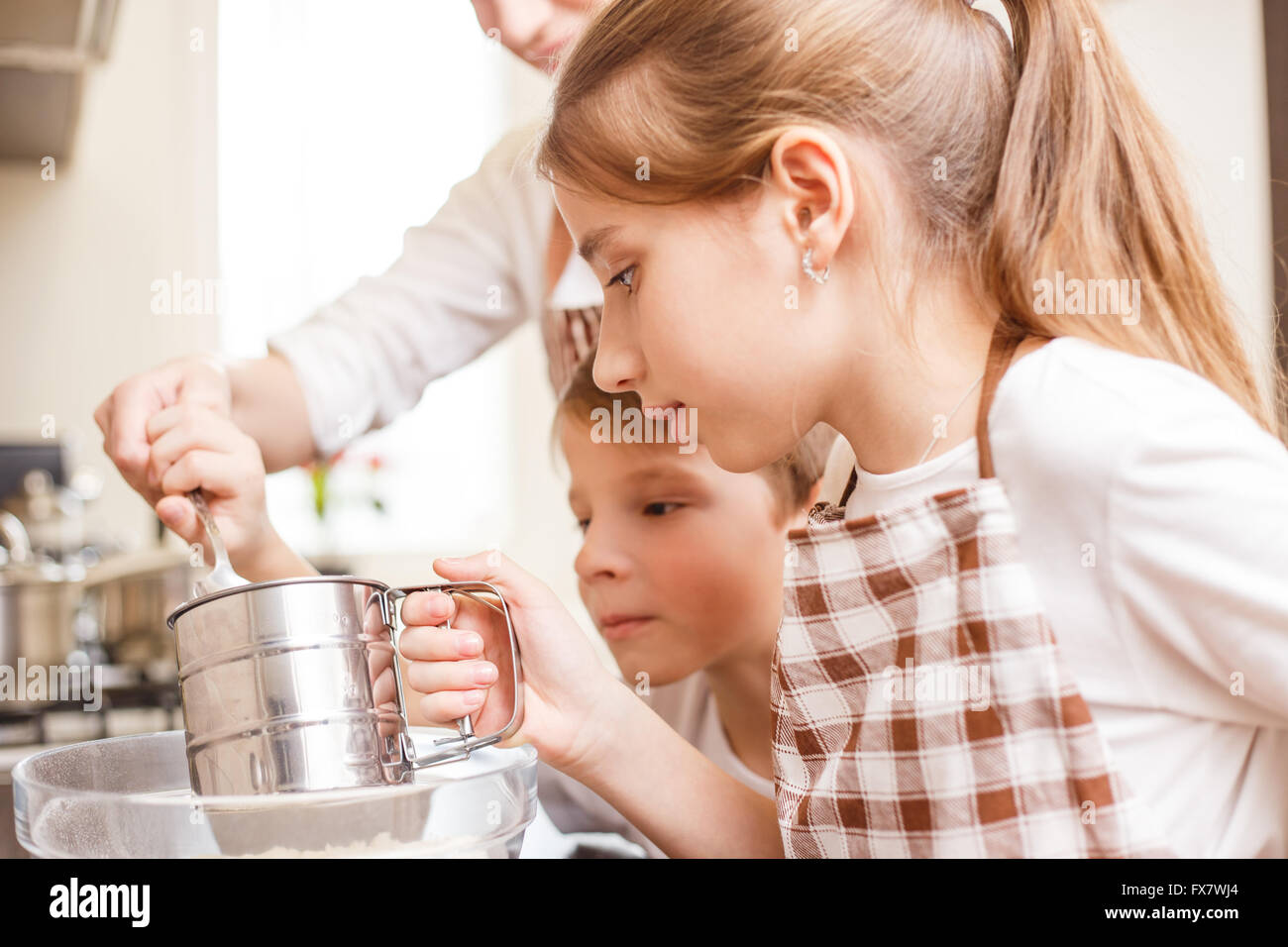 Family cooking background. Mum and children in the kitchen sieving ...