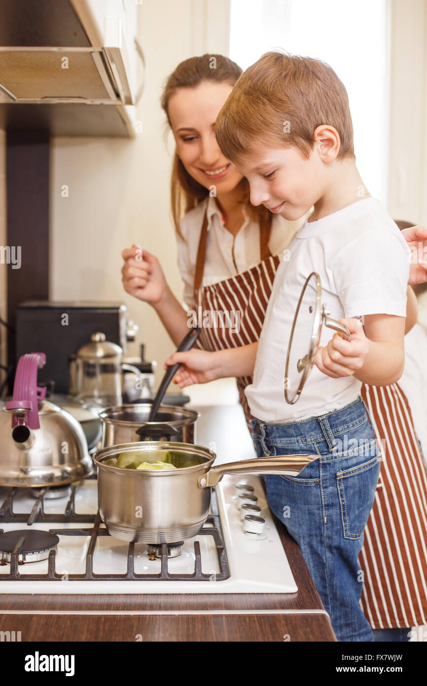 Small funny boy with his mother cooking with pots on the hob. Family ...