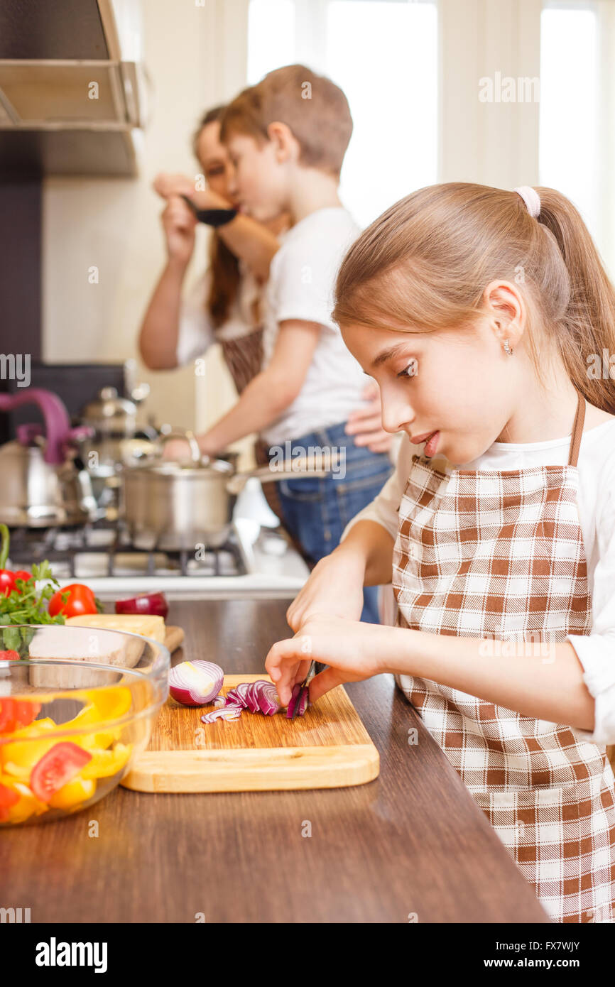 Teenage girl cooking together with her family in the kitchen. Caucasian ...