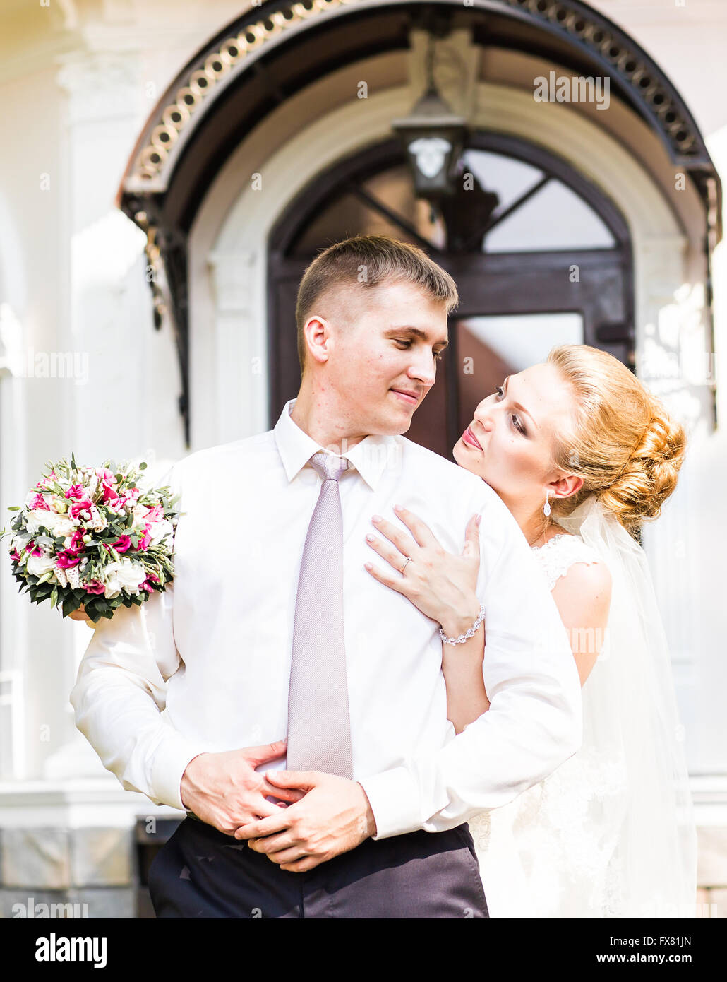 wedding couple hugging, bride holding a bouquet of flowers, the groom ...