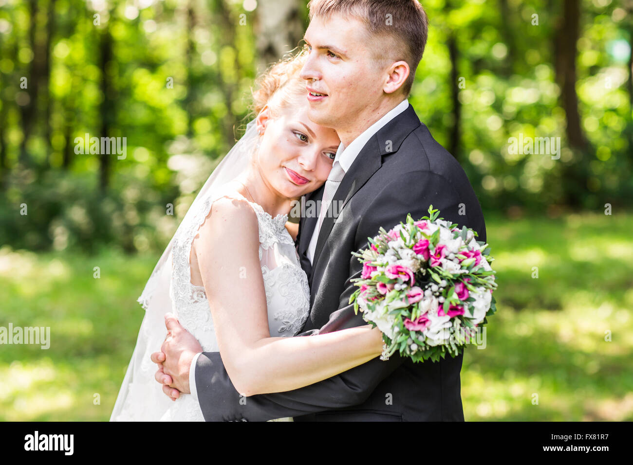 wedding couple hugging, bride holding a bouquet of flowers, the groom ...