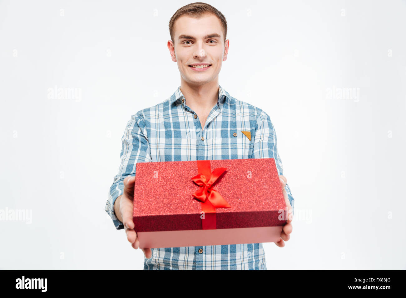 Smiling attractive young man giving you a gift over white background ...