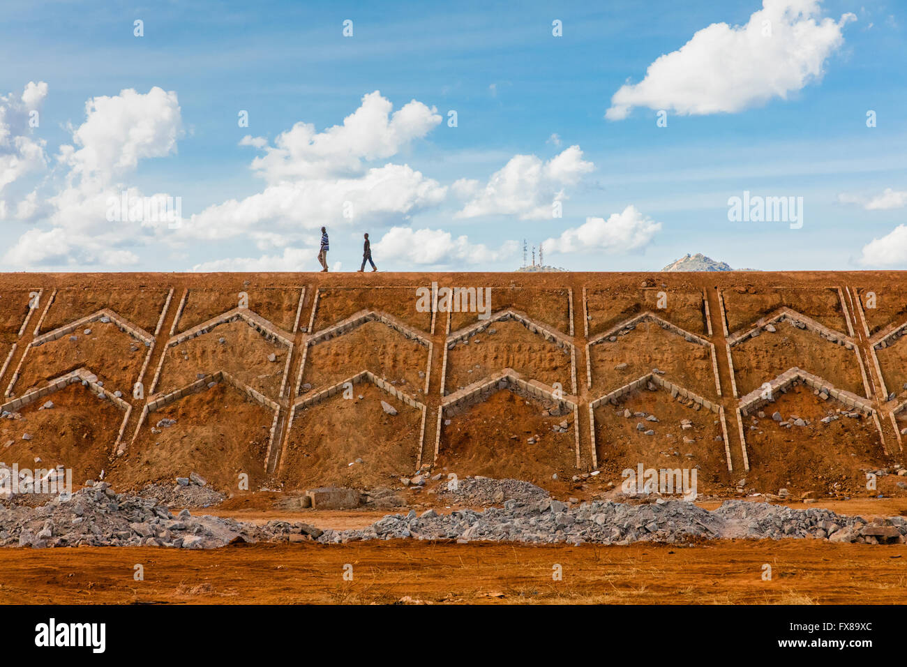 Two men walking along a newly built earth embankment of the Nairobi to ...
