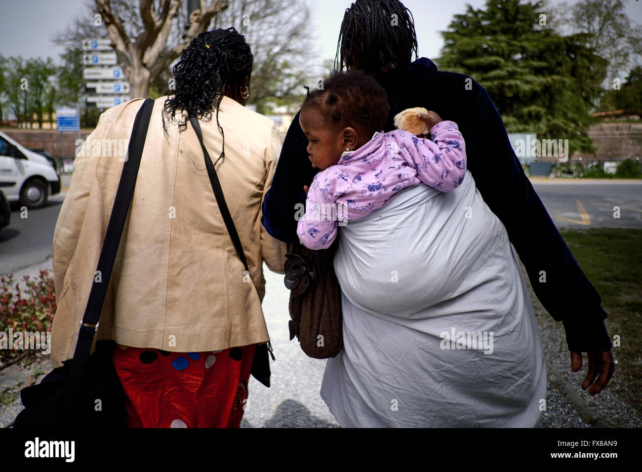 Two black women walking away from camera, one with a young child on her ...