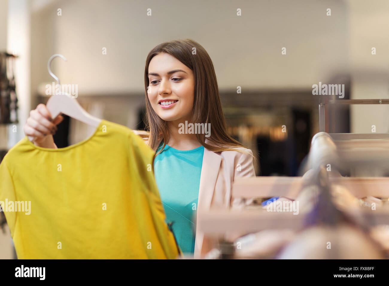 happy young woman choosing clothes in mall Stock Photo - Alamy