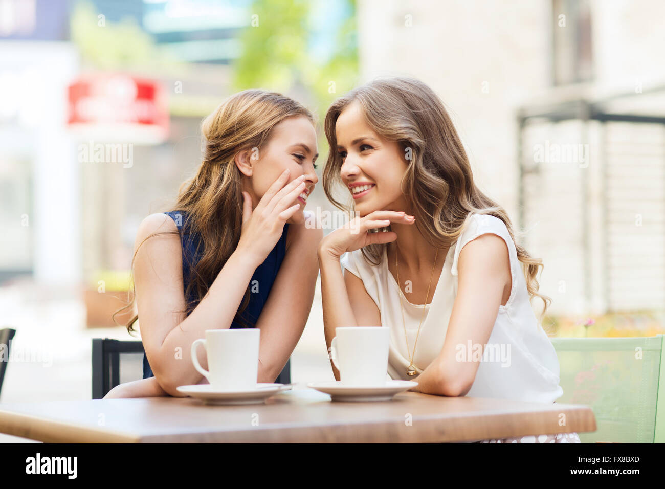 young women drinking coffee and talking at cafe Stock Photo - Alamy