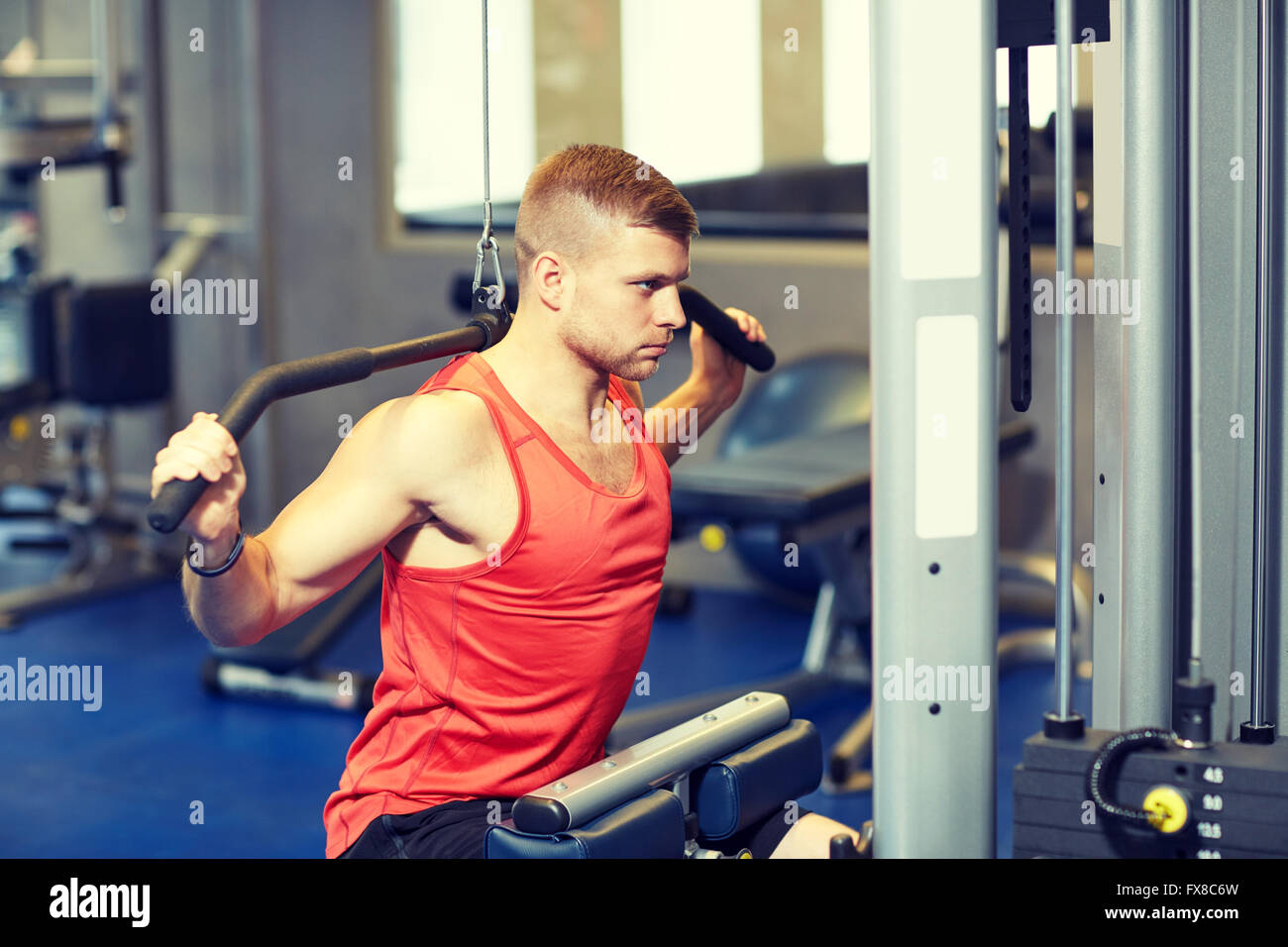 man flexing muscles on cable machine gym Stock Photo - Alamy