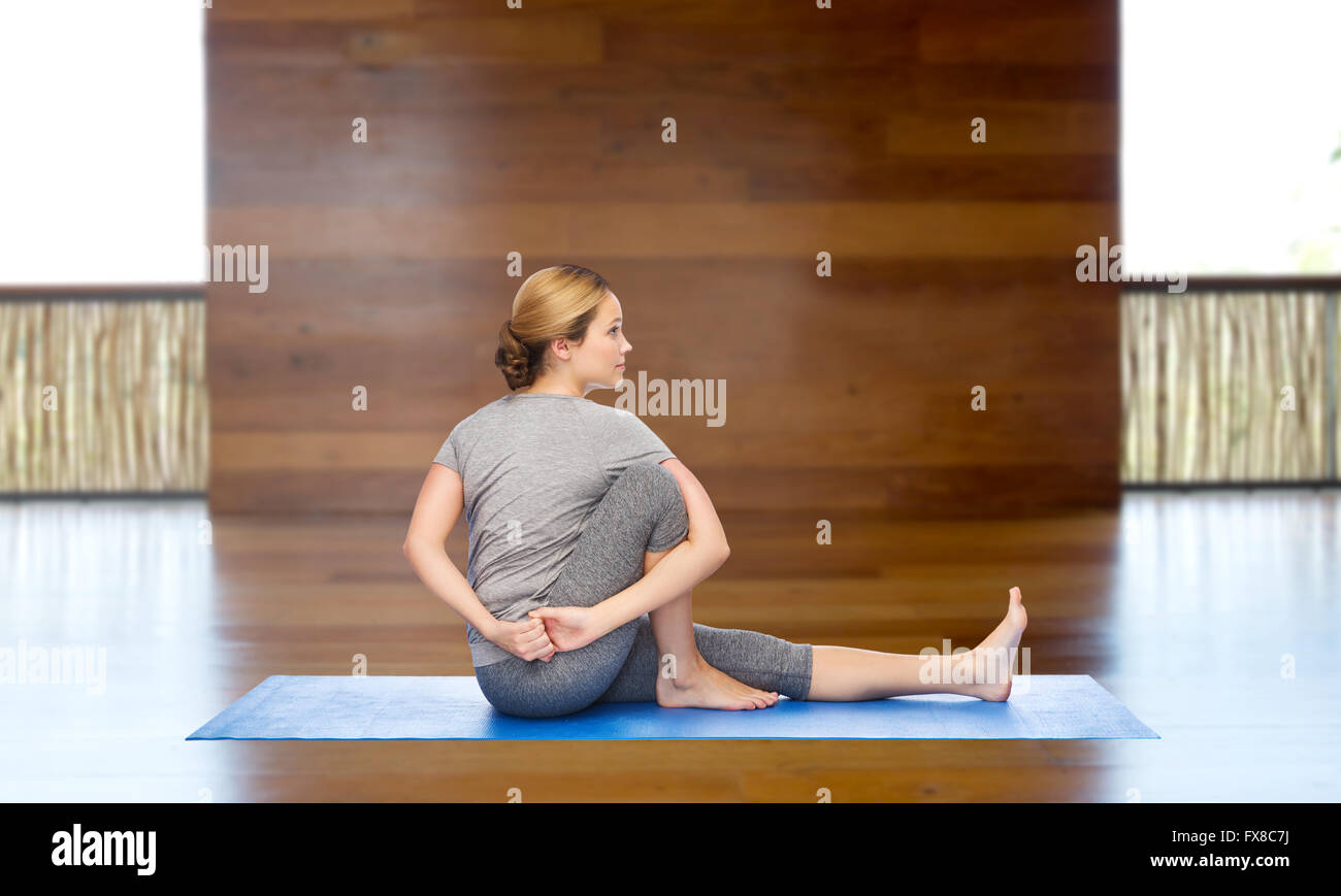 woman making yoga in twist pose on mat Stock Photo - Alamy