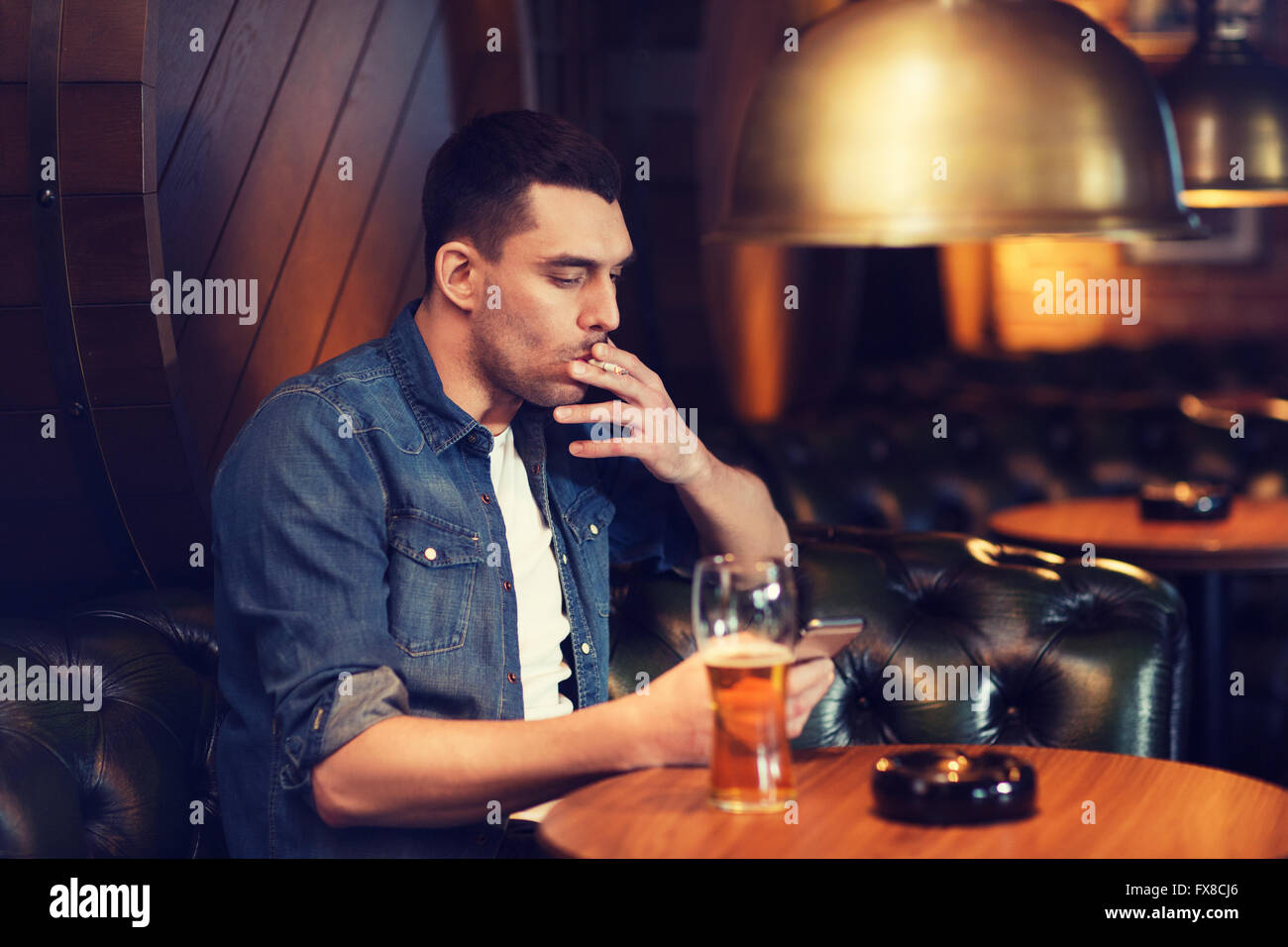 man drinking beer and smoking cigarette at bar Stock Photo - Alamy