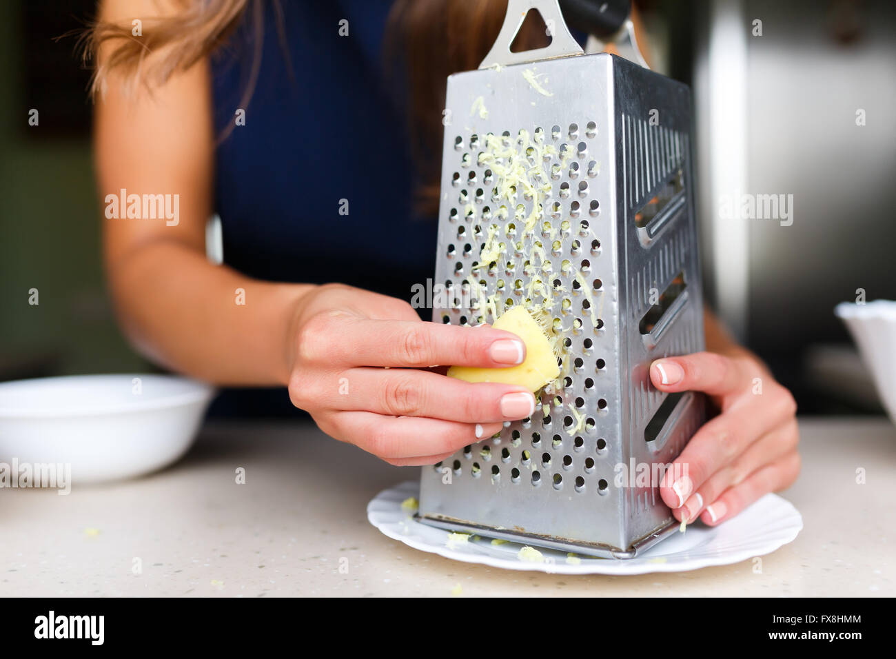 Young woman grating ginger in the kitchen Stock Photo - Alamy
