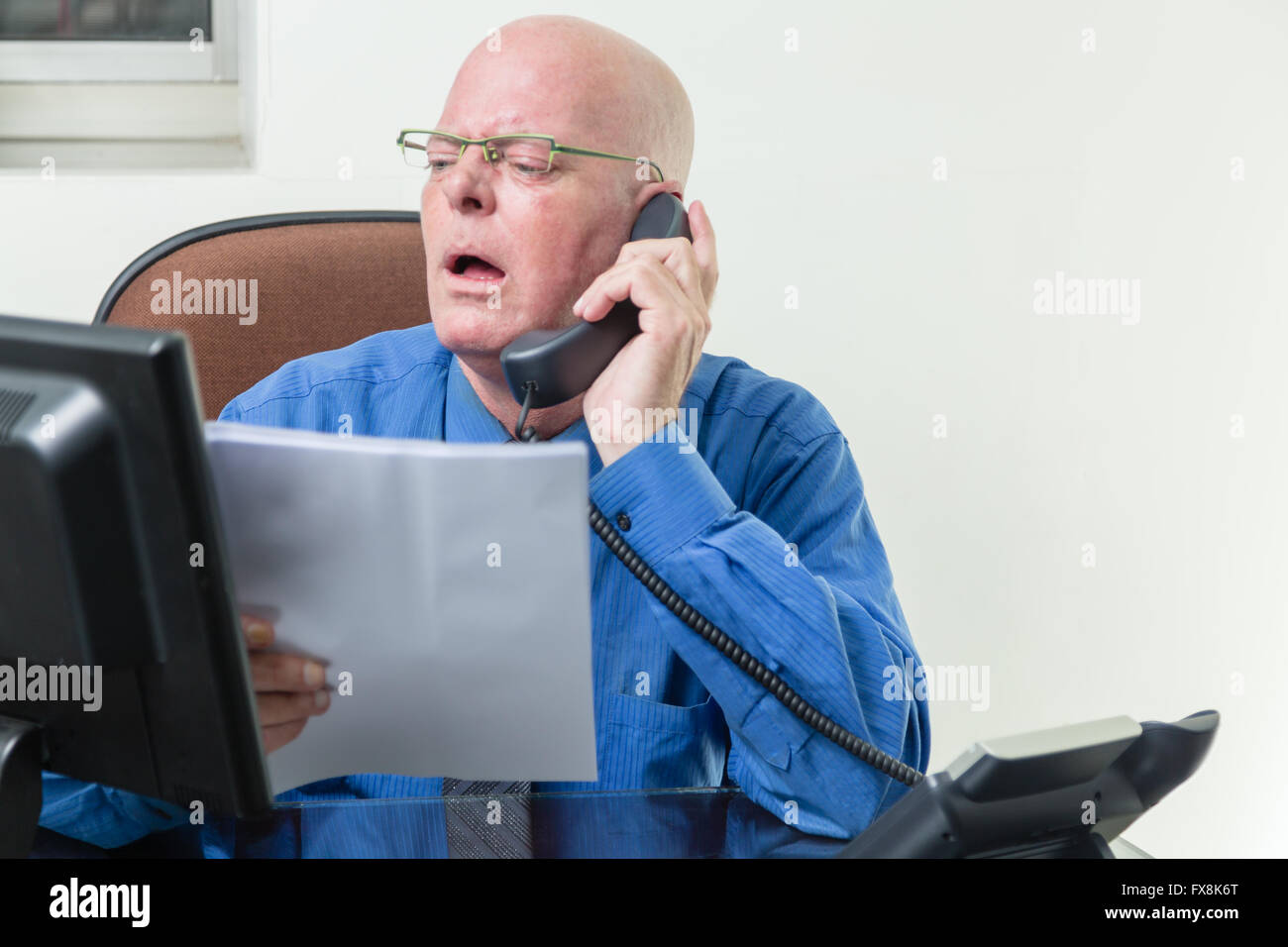Corporate worker at desk comparing written notes with computer data ...