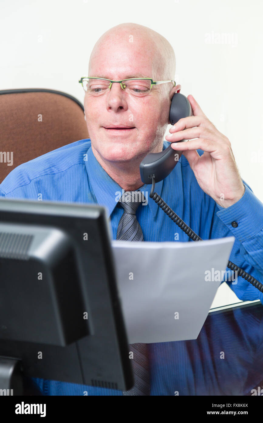 Corporate worker at desk comparing written notes with computer data ...