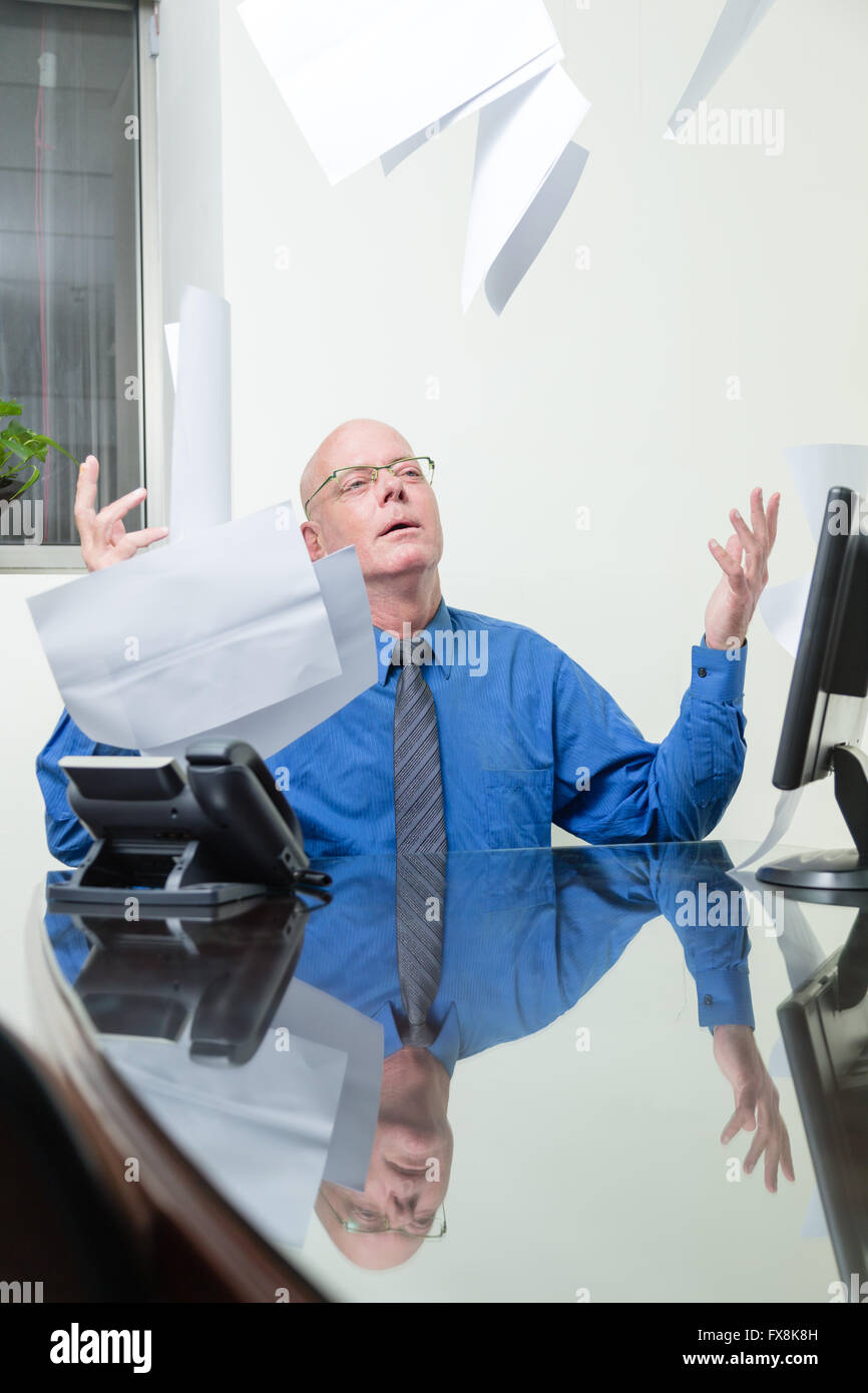 Frustrated office worker at desk throws paperwork in air Stock Photo ...