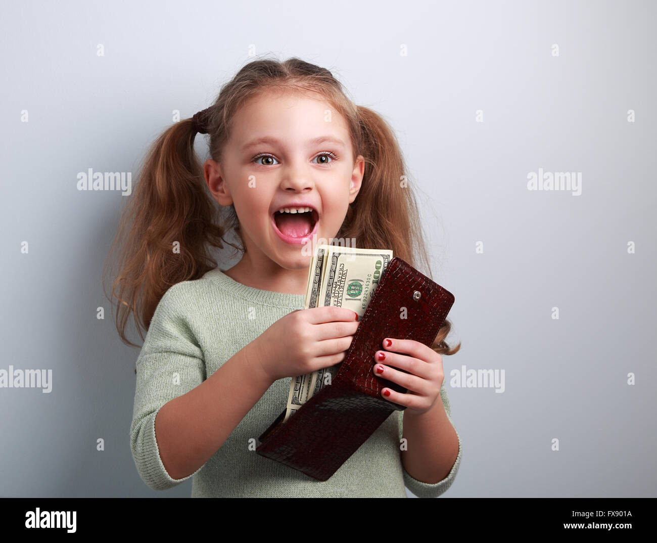 Cute happy kid girl holding wallet with much dollars with open mouth ...