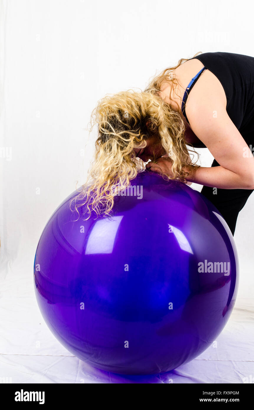 Young woman inflating a huge purple balloon by mouth Stock Photo - Alamy