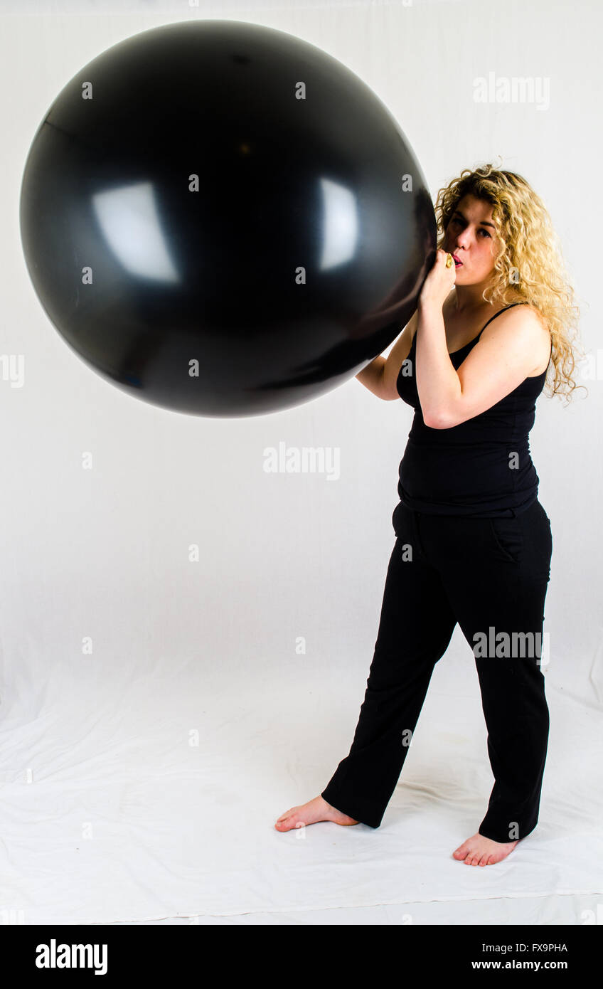 Young woman inflating a huge black balloon by mouth Stock Photo - Alamy
