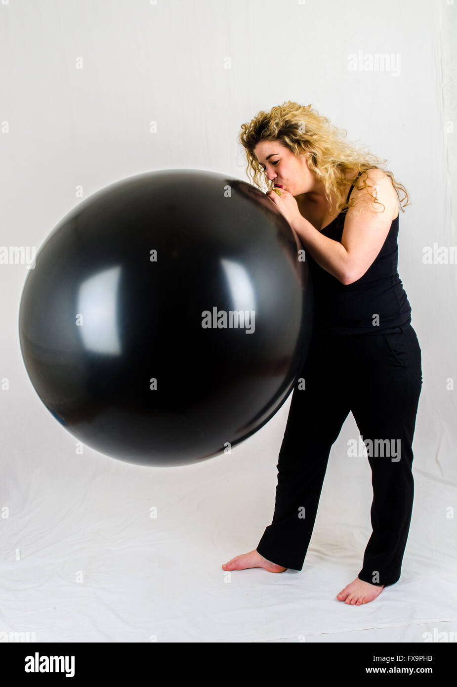Young woman inflating a huge black balloon by mouth Stock Photo - Alamy