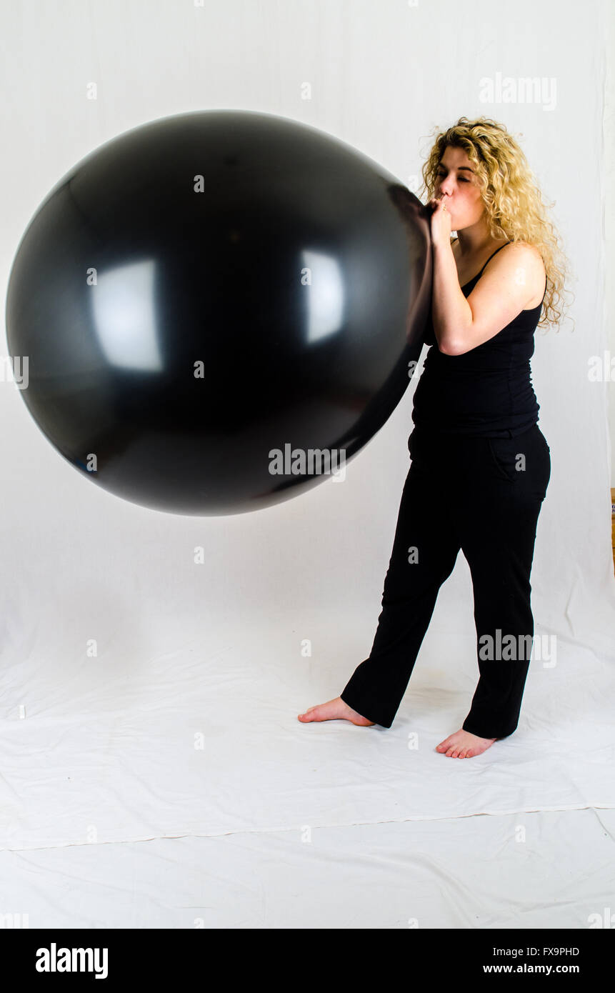 Young woman inflating a huge black balloon by mouth Stock Photo - Alamy