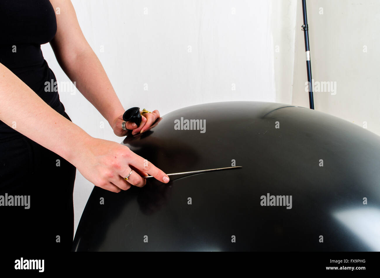 Young woman with a huge balloon and large needle Stock Photo - Alamy