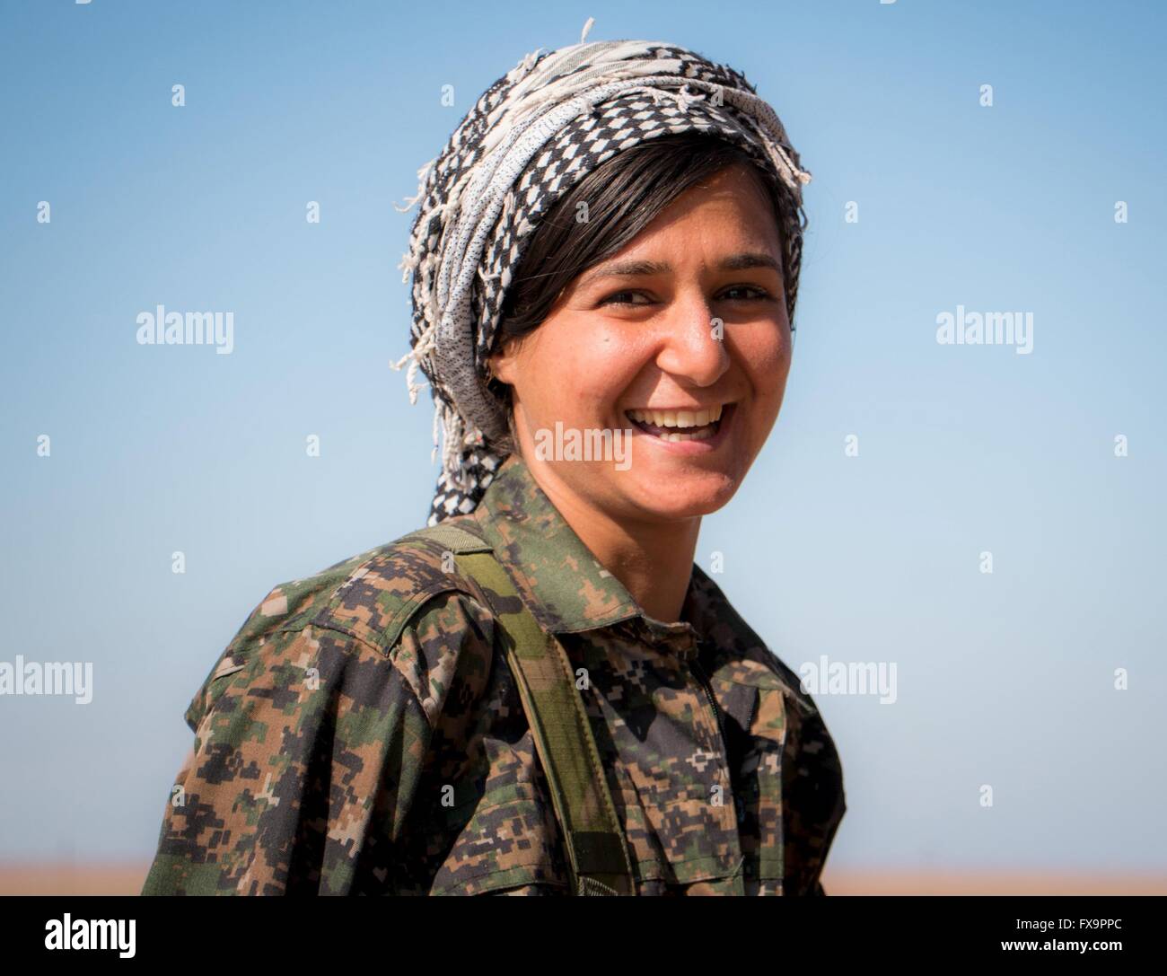 A Kurdish YPG woman fighter smiles in uniform near the front lines ...