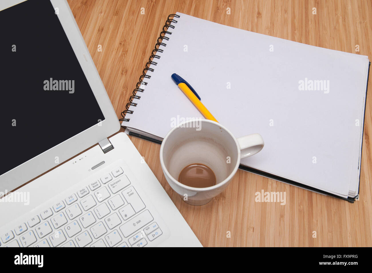 Laptop and notepad on the table with an empty coffee cup Stock Photo ...
