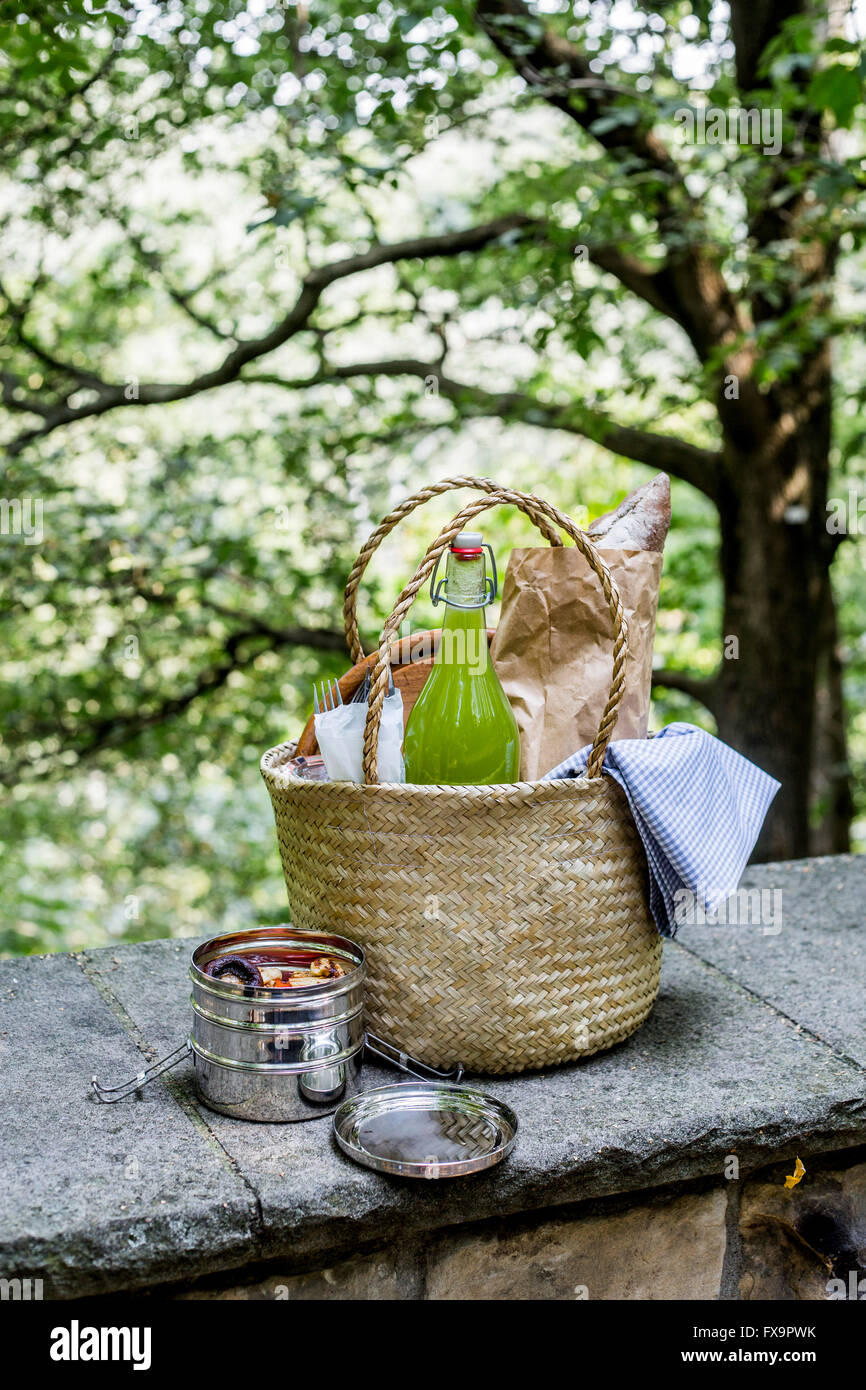 Picnic basket on wall with lemonade bottle, lunch box, artisan bread in ...