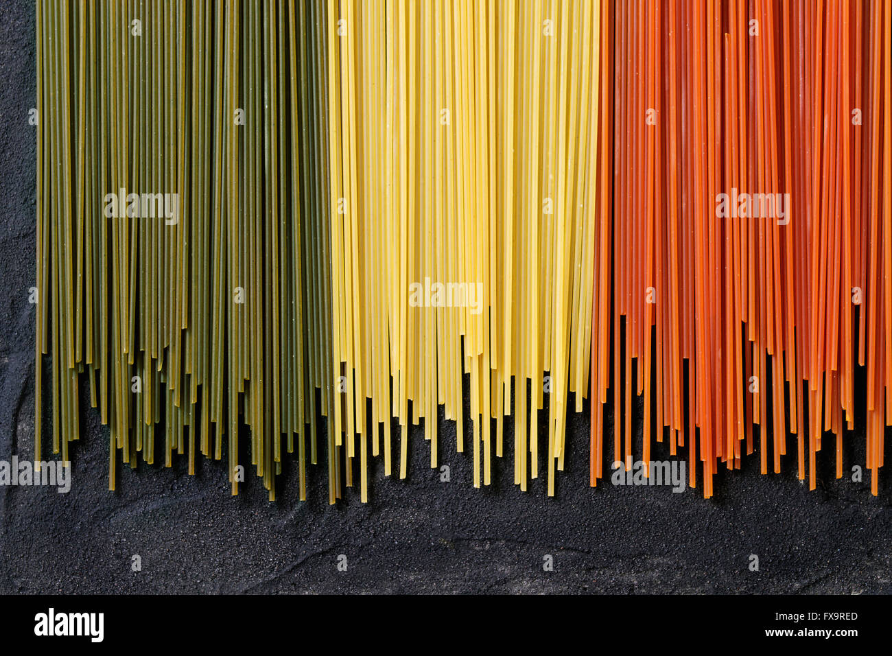 Dry colorful pasta spaghetti as italian flag over black textured ...
