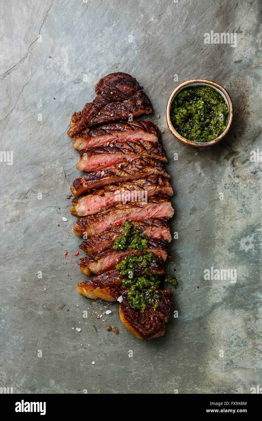 Sliced grilled beef barbecue Striploin steak with chimichurri sauce on ...