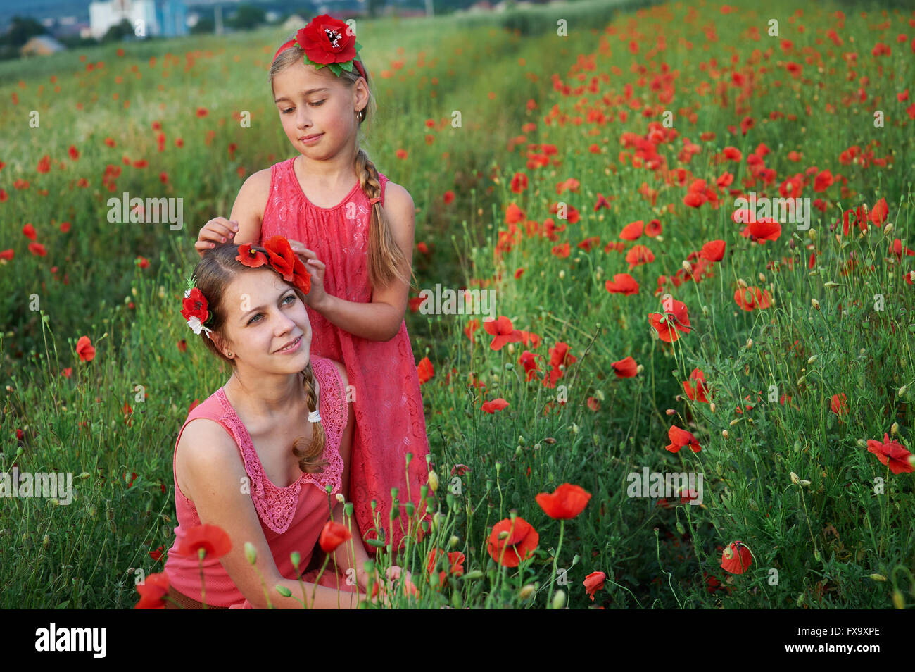 two girls in red dress walking on poppy field Stock Photo - Alamy