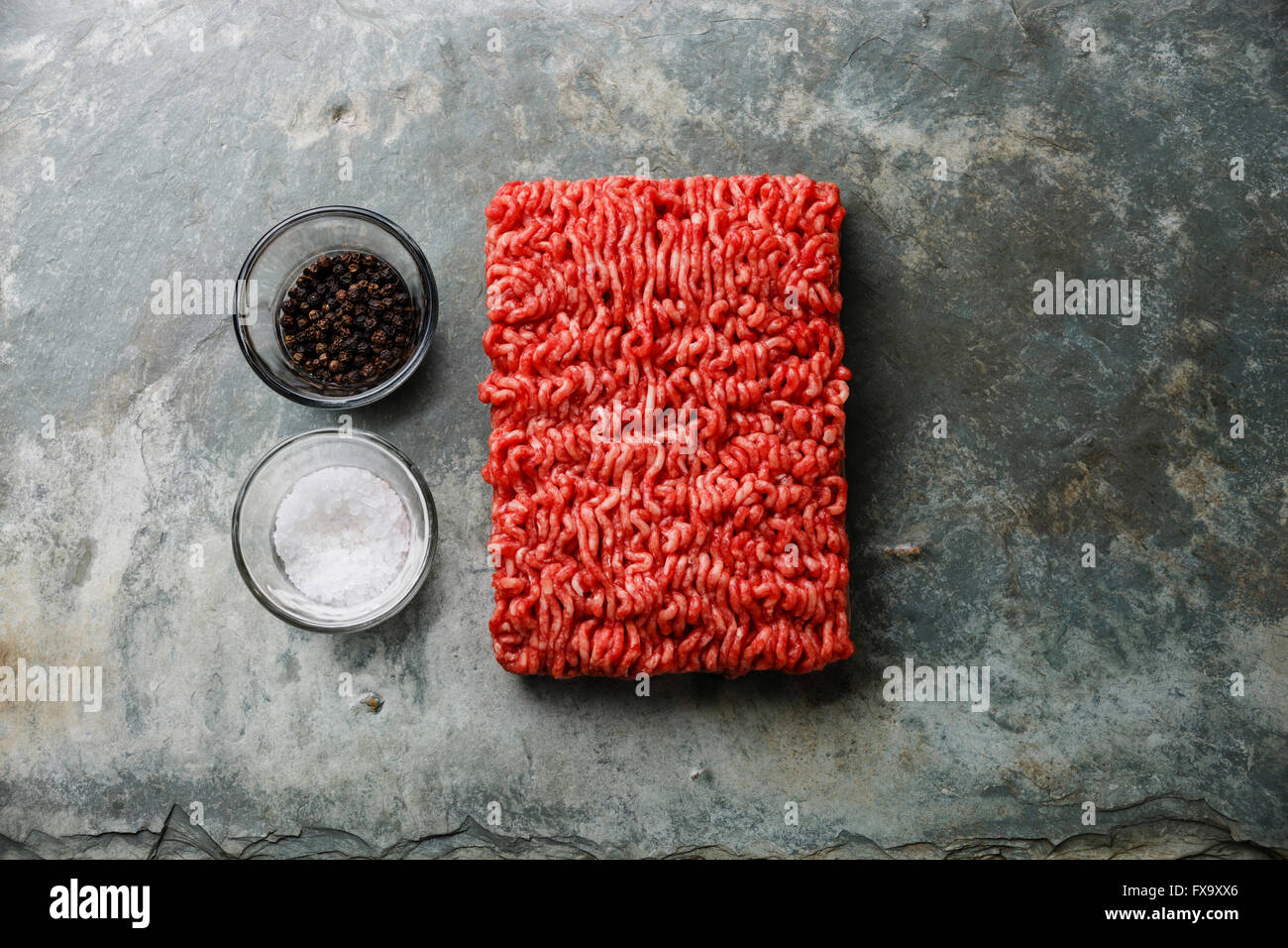 Minced meat forcemeat on stone slate background with salt and pepper ...