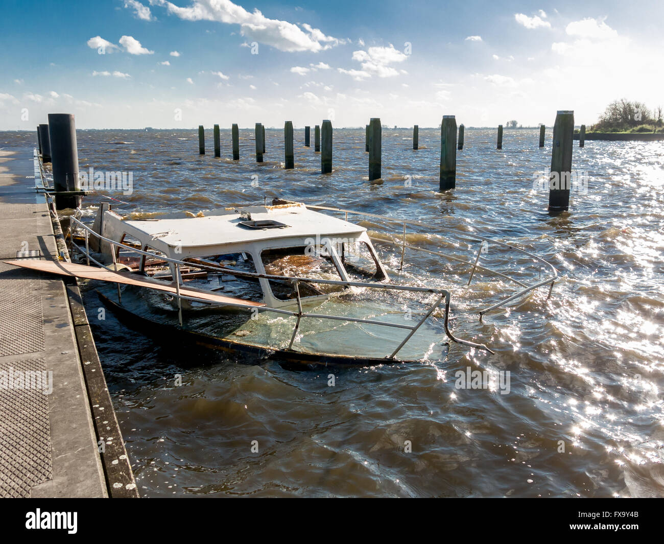 Half sunken motor yacht in old harbor with jetty and pillars ...