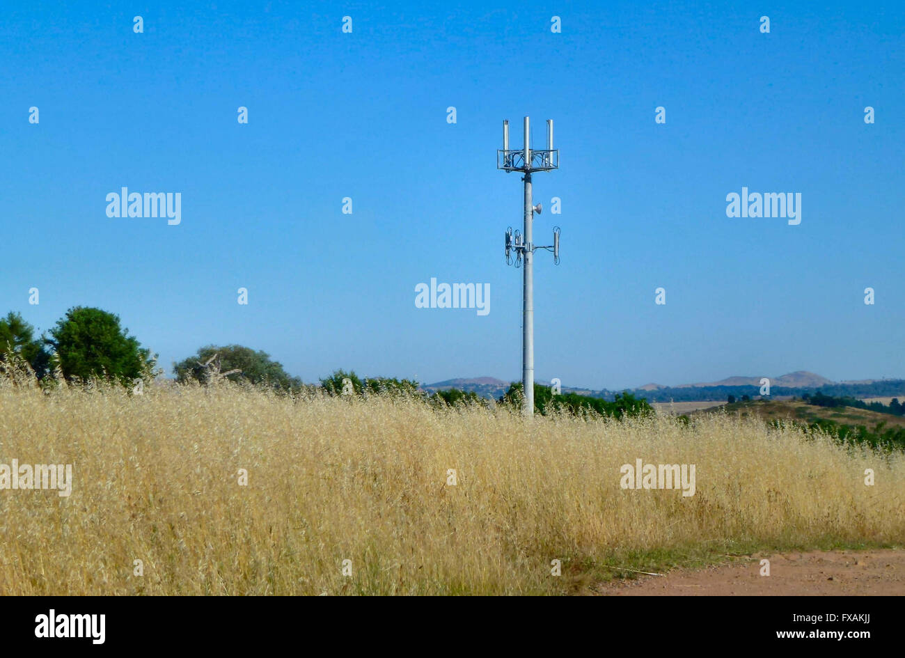 Phone telecommunications tower in grass field against blue sky Stock ...