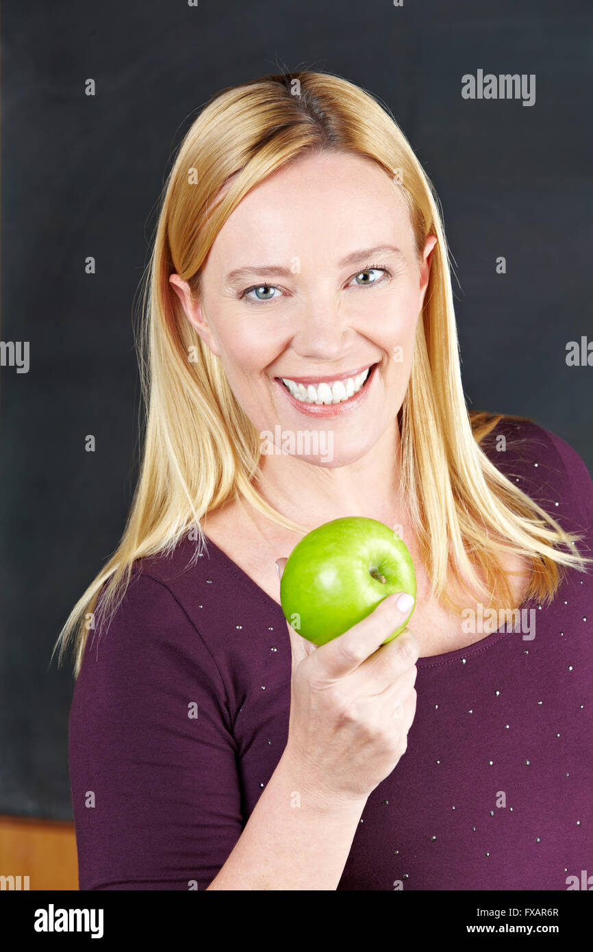 Smiling female teacher holding a green apple Stock Photo - Alamy