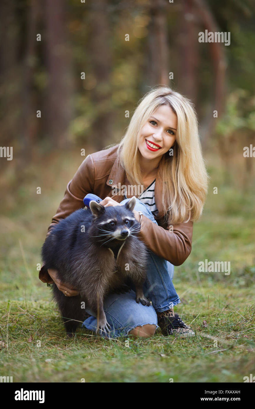 Portrait of attractive young woman with raccoon in a forest Stock Photo ...
